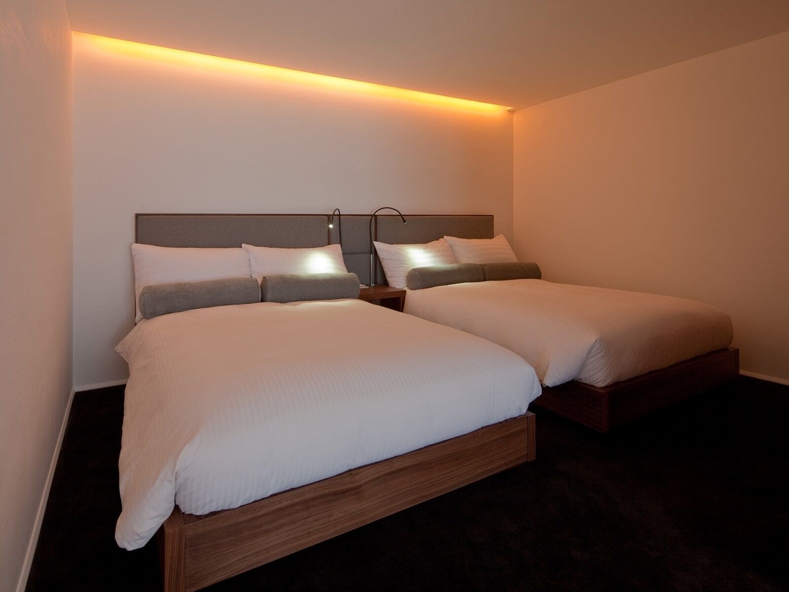 Uma cama de casal com estrutura de madeira e duas mesas de cabeceira, cada uma com uma luminária.