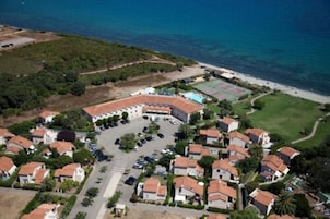 Vista aérea de uma área residencial à beira-mar, com casas, estacionamento e praia.