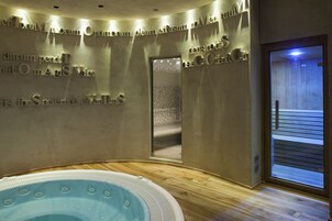 Uma área de spa com hidromassagem, piso de madeira e uma parede com texto gravado.