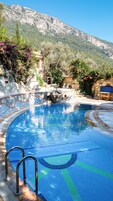 Piscina com parede de pedra e montanhas ao fundo.