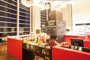Um bar com área de lounge e um cardápio em lousa listando preços de bebidas e petiscos.
