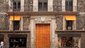 Um edifício com uma grande porta de madeira, um letreiro que diz 'Café Punta del Sol' e uma loja da 'BUNEDA COVALIN'.