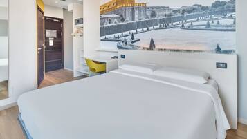 Quarto de hotel moderno com uma cama grande, uma escrivaninha e uma cadeira.