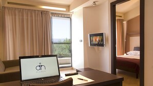 Quarto de hotel com escrivaninha, computador portátil e cama.