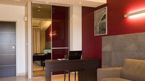 Quarto moderno com escrivaninha, sofá e um espelho grande.