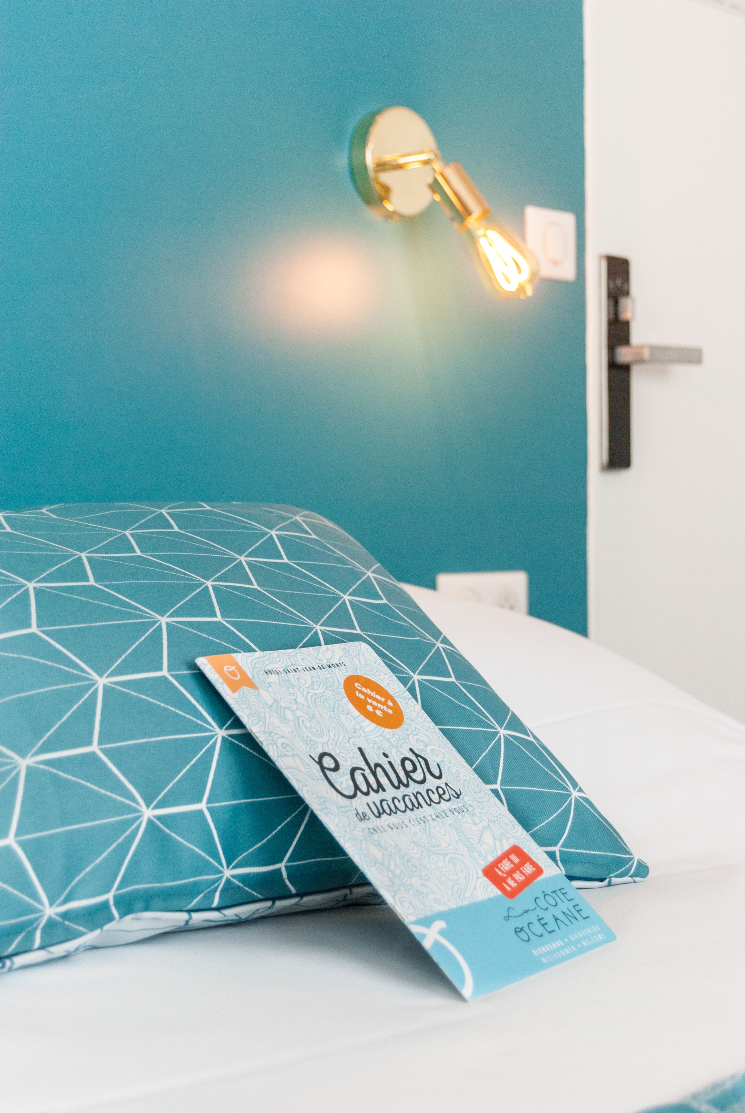 Uma cama com travesseiro de padrão geométrico em tons de verde-água e uma etiqueta indicando um desconto.