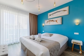 Quarto de hotel com cama, mesa de cabeceira, abajur e obras de arte na parede.