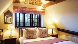 Quarto com uma cama grande, duas luminárias de cabeceira, uma janela com vista e um espelho na parede.