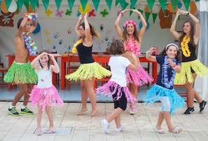 Um grupo de pessoas dançando em uma sala com decorações coloridas e impressões de mãos nas paredes.
