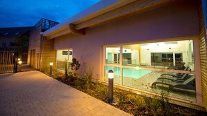 Um edifício moderno com piscina, janelas amplas e um caminho de tijolos.