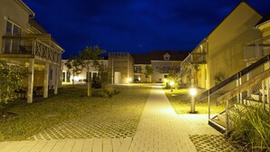 Um pátio com calçada pavimentada, edifícios com varandas e áreas de estar ao ar livre.
