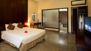 Quarto de hotel com uma cama grande, luminárias de cabeceira, televisão, espelho e porta deslizante que dá para uma varanda.