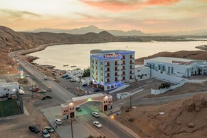 Um hotel com vista para a água e montanhas ao fundo.