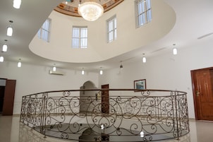 Um átrio amplo com teto alto, uma escadaria espiral central e um elegante guarda-corpo de ferro forjado.