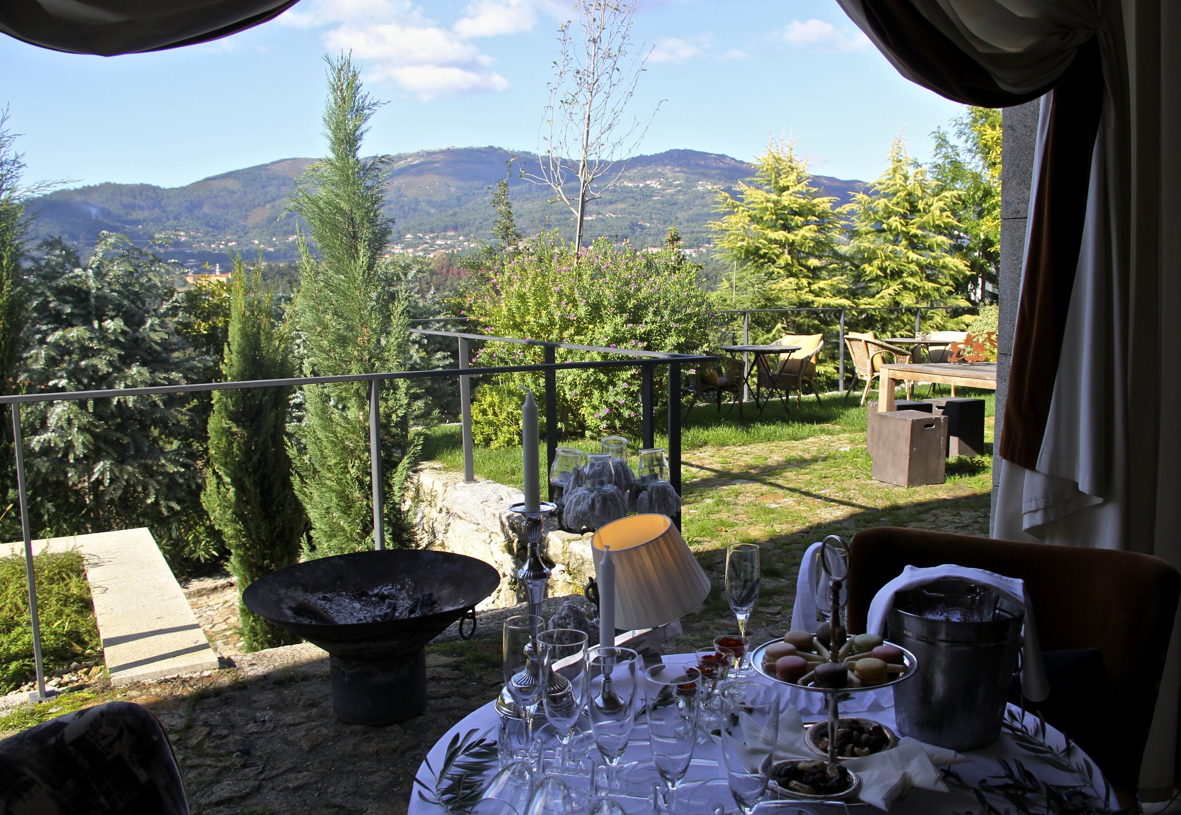 Uma área de refeições ao ar livre com uma mesa posta para uma refeição, com vista para uma paisagem montanhosa.