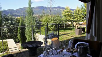 Uma área de refeições ao ar livre com uma mesa posta para uma refeição, com vista para uma paisagem montanhosa.
