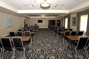 Uma sala de conferência com carpete estampado, várias mesas e cadeiras dispostas para reuniões.