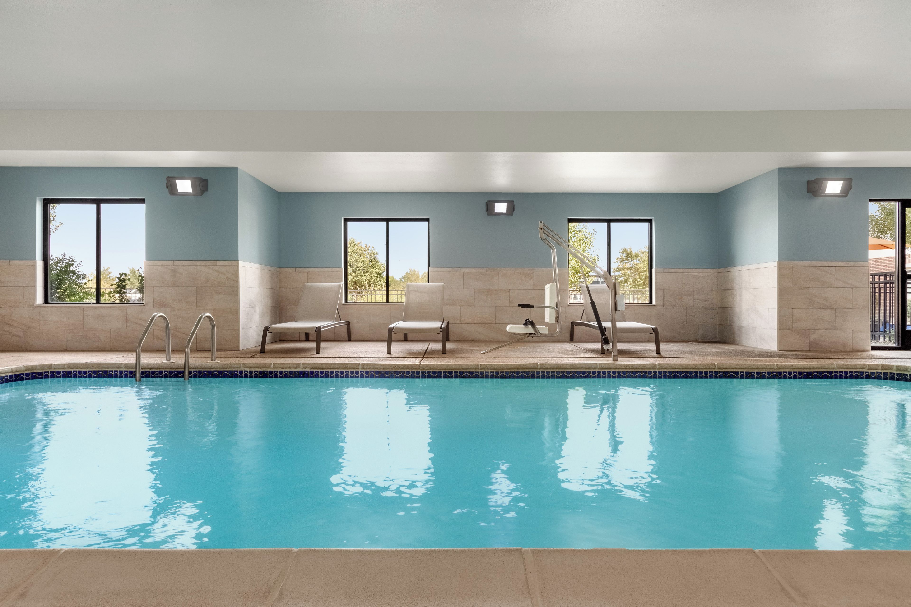 Piscina com superfície de água azul cristalina, cercada por espreguiçadeiras e um toldo.