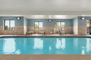 Piscina com superfície de água azul cristalina, cercada por espreguiçadeiras e um toldo.