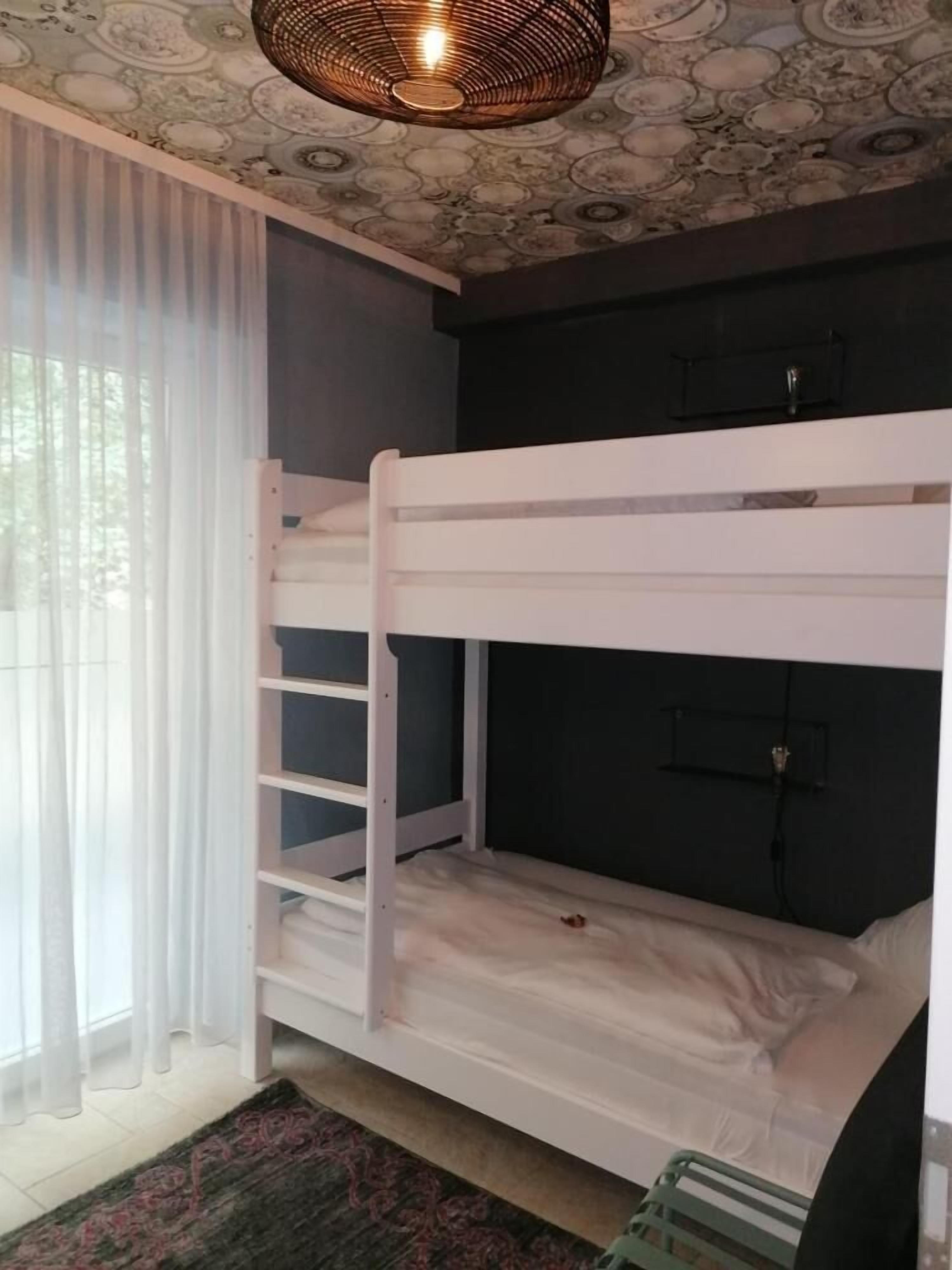 Quarto com beliche, teto estampado, cabeceira branca e parede preta com prateleira.