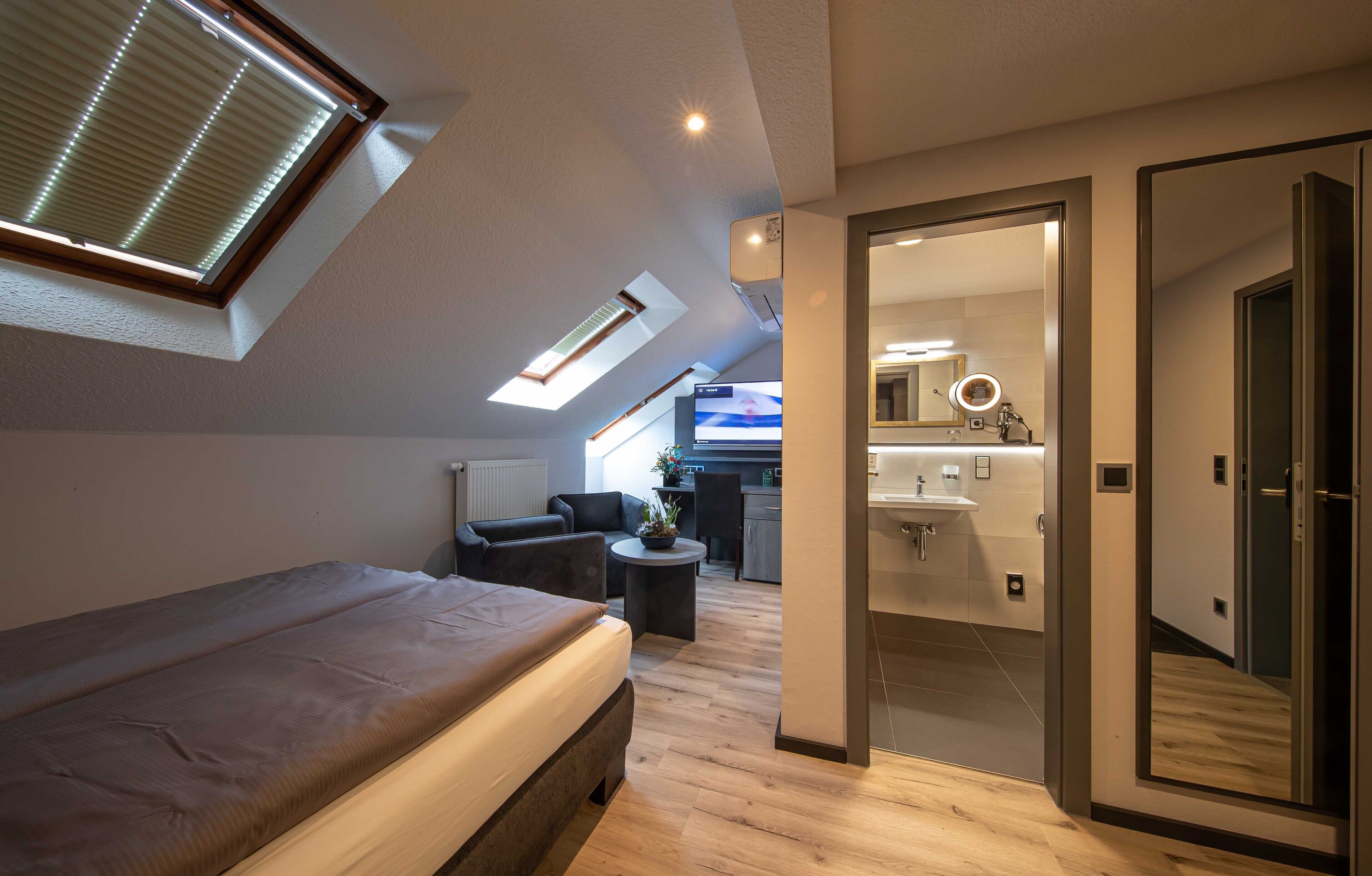 Quarto moderno com claraboia, sofá, uma mesinha e vista para uma área integrada de cozinha e banheiro.