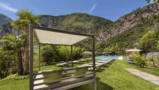 Uma área à beira da piscina com espreguiçadeiras e um pérgola.