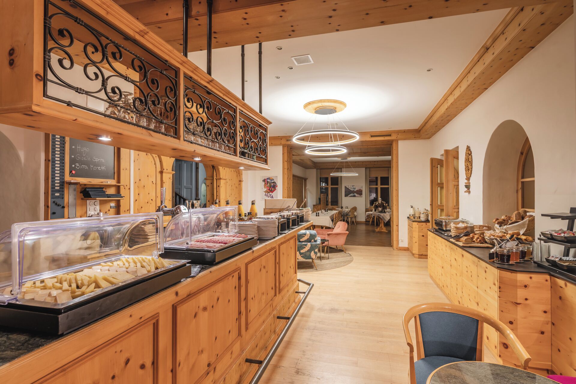 Uma área de buffet com diversos alimentos, painéis de madeira e um balcão comprido.