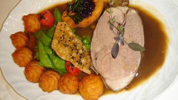 Prato de comida com carne assada, legumes e molho.