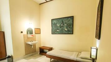 Quarto pequeno e limpo, com uma cama de solteiro, pia e um quadro na parede.