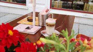 Uma mesa com bebida, cardápio e vela em frente a um café.