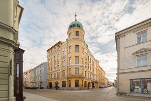 Um edifício histórico com uma cúpula imponente e arquitetura clássica, situado numa rua de calçada.