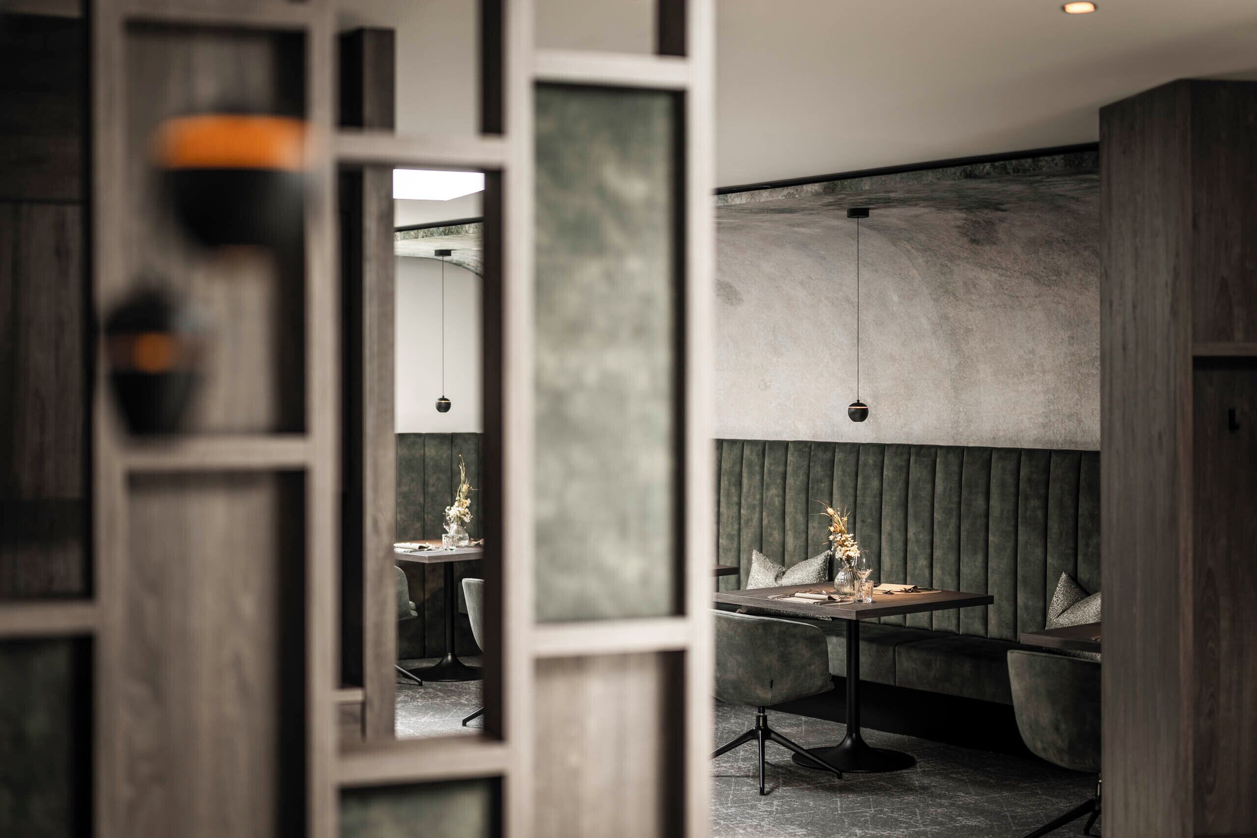 Um interior moderno com área de estar, uma mesa com um vaso e uma luminária pendente.