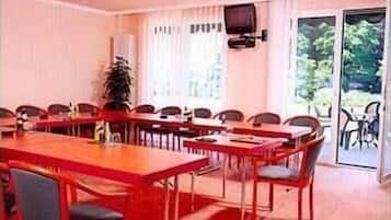 Uma sala de conferências com uma mesa comprida e cadeiras, uma televisão na parede e vista para o verde lá fora.