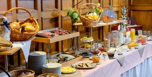 Buffet variado com carnes, queijos, frutas e bebidas.