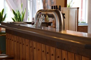 Uma área de bar com balcão de aço inoxidável, painéis de madeira e torneira de cerveja.