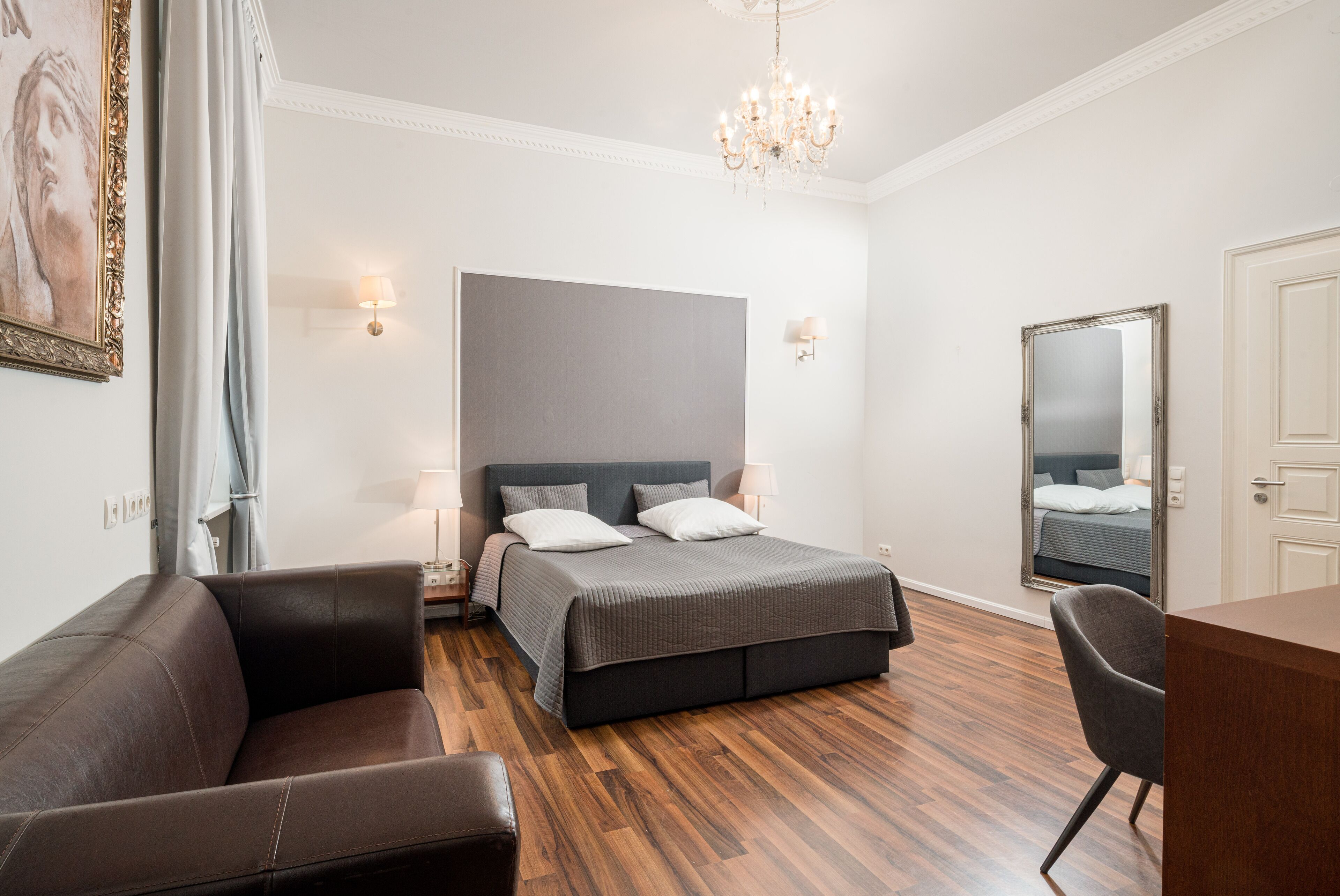 Um quarto moderno com uma cama grande, um sofá de couro, uma escrivaninha e um lustre.
