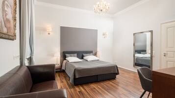 Um quarto moderno com uma cama grande, um sofá de couro, uma escrivaninha e um lustre.