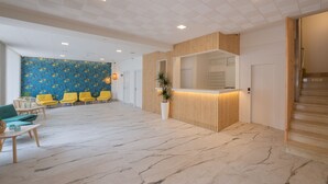 Um hall amplo com balcão de atendimento, área de estar e parede estampada.