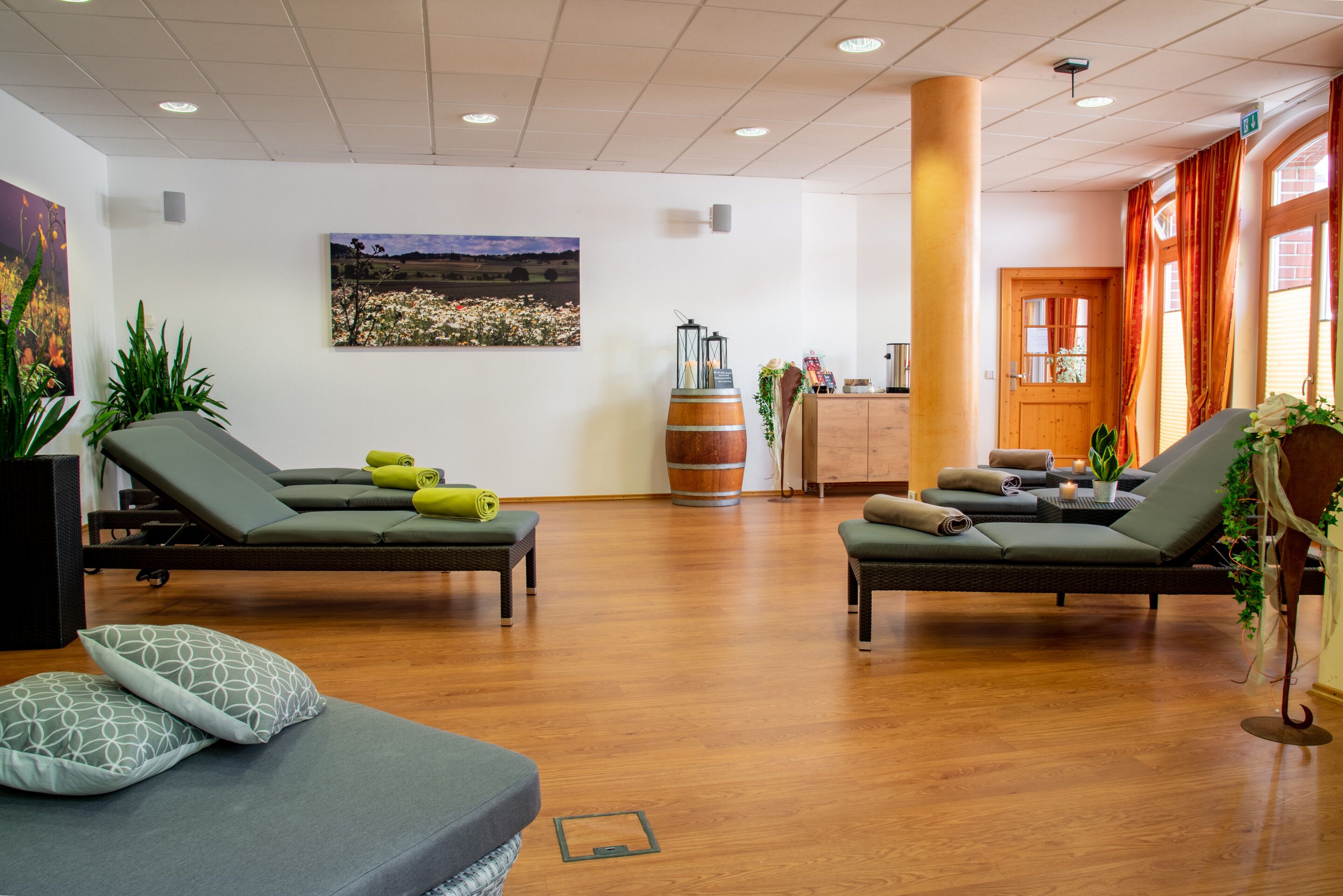 Área de spa com duas poltronas reclináveis, um barril de madeira e uma mesa de recepção.