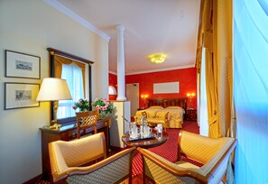 Quarto de hotel com uma cama, uma escrivaninha com abajur, duas cadeiras e uma pequena mesa com bandeja.