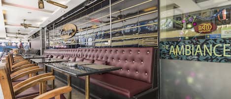 Um restaurante com área de bar, assentos acolchoados e ventiladores de teto.