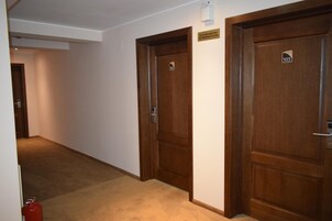 Um corredor com três portas de madeira, cada uma delas numerada.