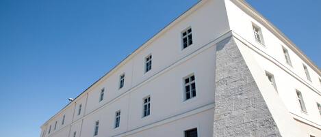 Um edifício de vários andares com fachada branca e canto em pedra.