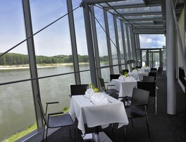 Um restaurante com mesas preparadas para refeições, com vista para um rio.