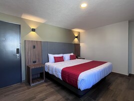 Quarto de hotel moderno com uma cama grande, cabeceira de madeira, mesas de cabeceira e iluminação embutida na parede.
