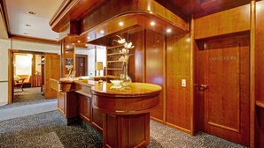 Uma área de recepção de hotel com um balcão de madeira, um vaso com flores e uma porta com a inscrição 'DIREKTIONS'.