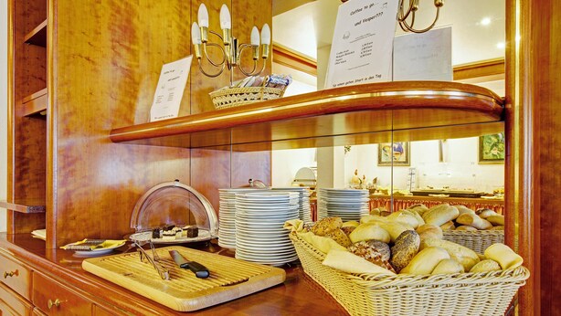 Disposição de buffet com pratos, talheres e cestas de pão.