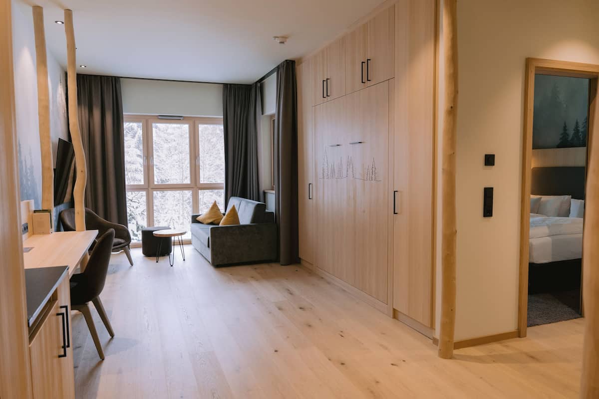 Quarto moderno com escrivaninha de madeira, sofá, cama e guarda-roupa.