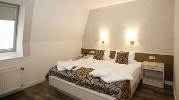 Quarto de hotel com uma cama grande, duas mesas de cabeceira, uma janela e um radiador.
