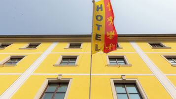 Um edifício amarelo com várias janelas e uma bandeira com a palavra 'HOTEL'.